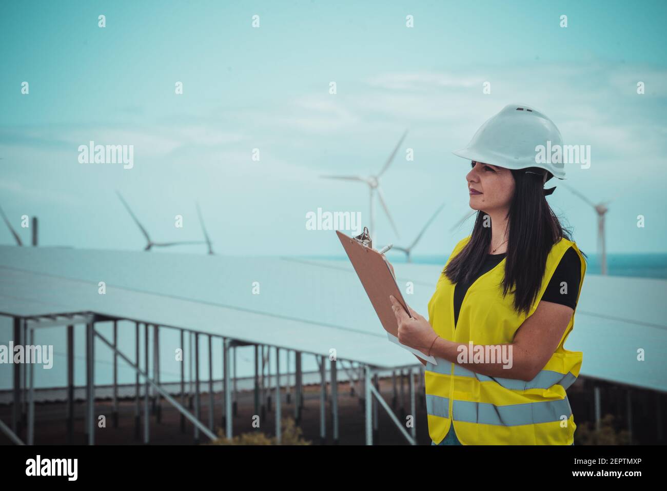 adult female engineer supervises solar panels and windmills in a ...