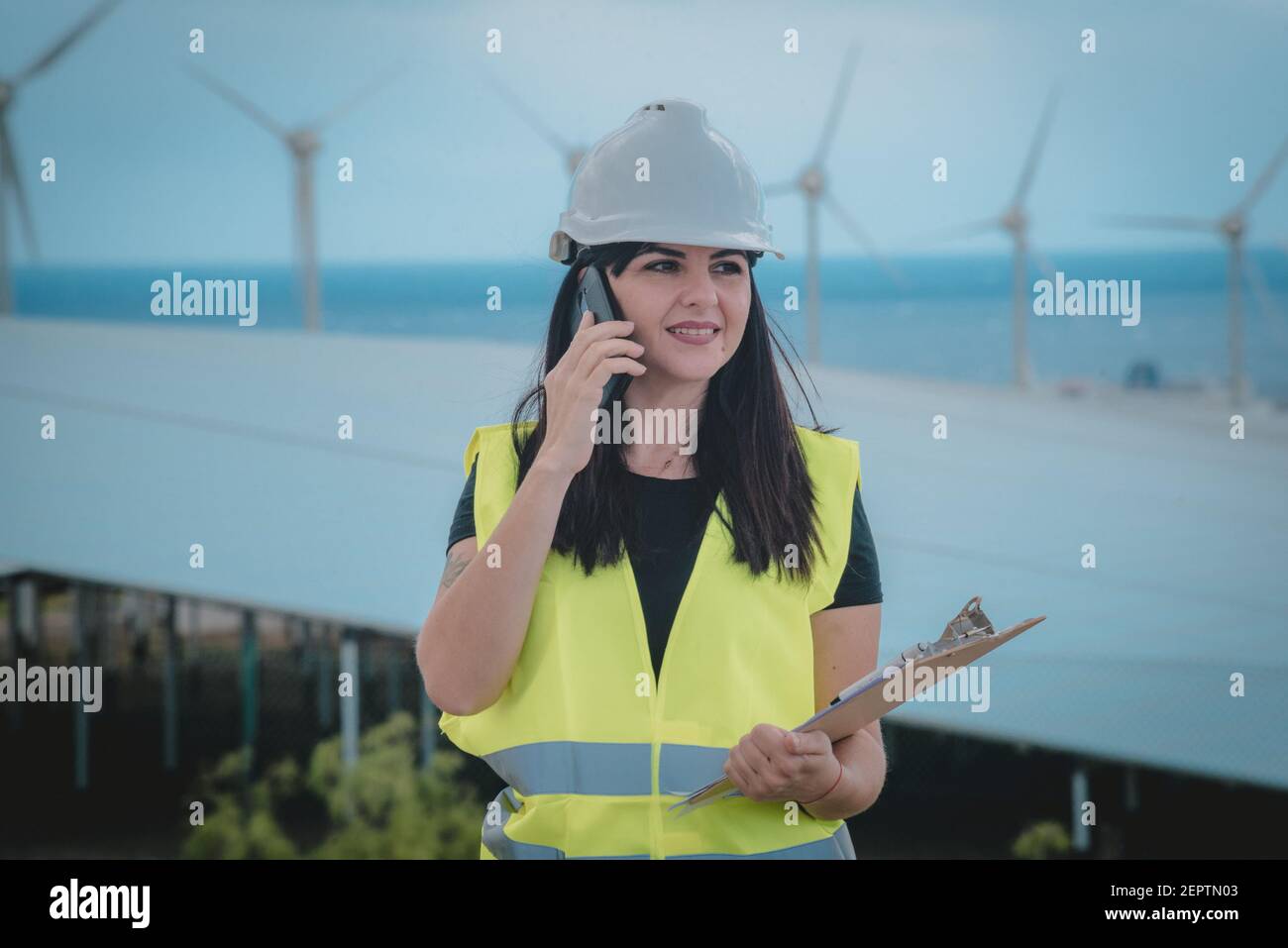 adult female engineer supervises solar panels and windmills in a ...