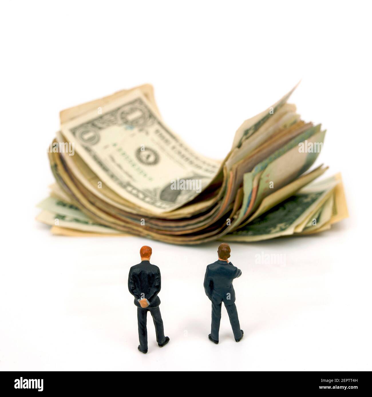 Two businessmen observing a large pile of cash against a plain ...