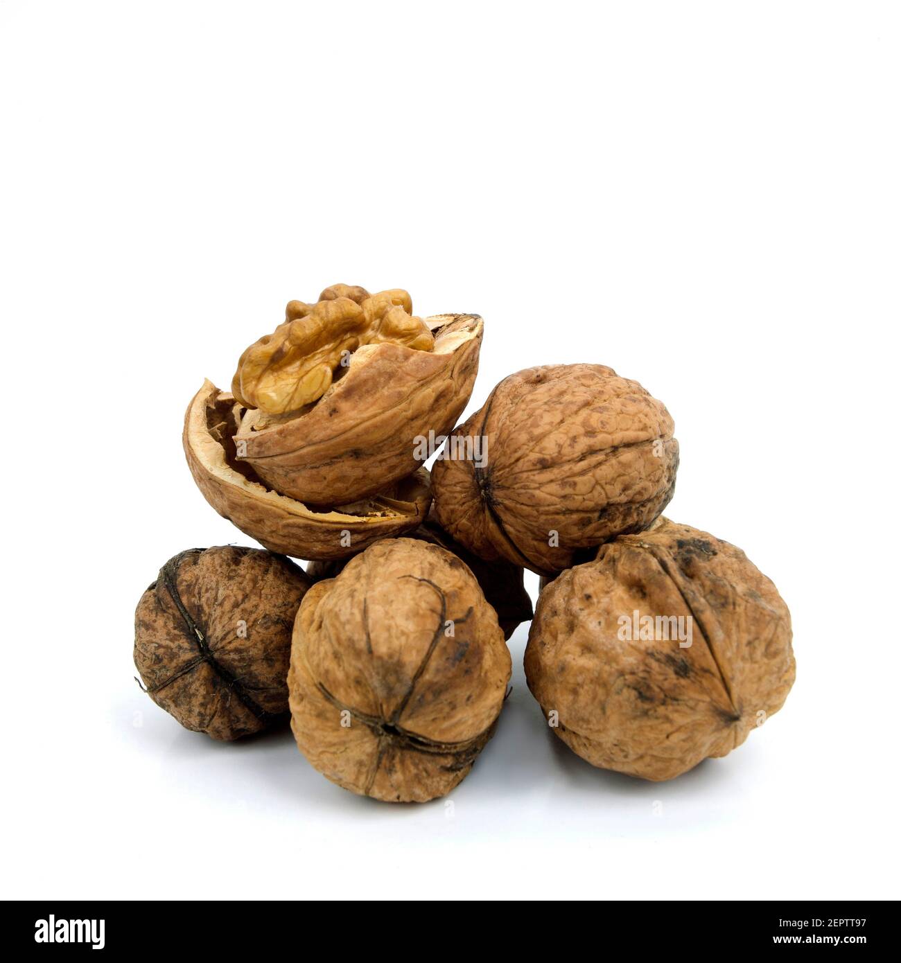 Walnuts piled on a white surface with one cracked open, showcasing the ...