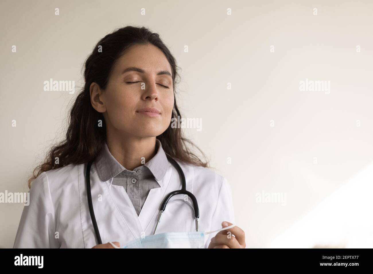 Head shot relaxed female doctor taking off medical face mask Stock ...