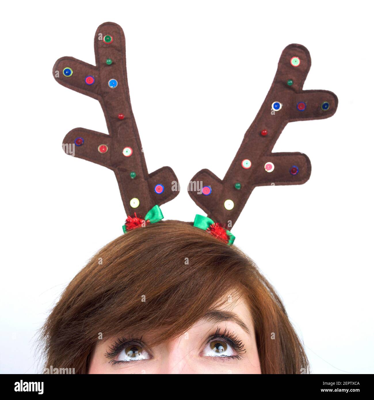 A young person wearing festive reindeer antlers, looking up with a ...