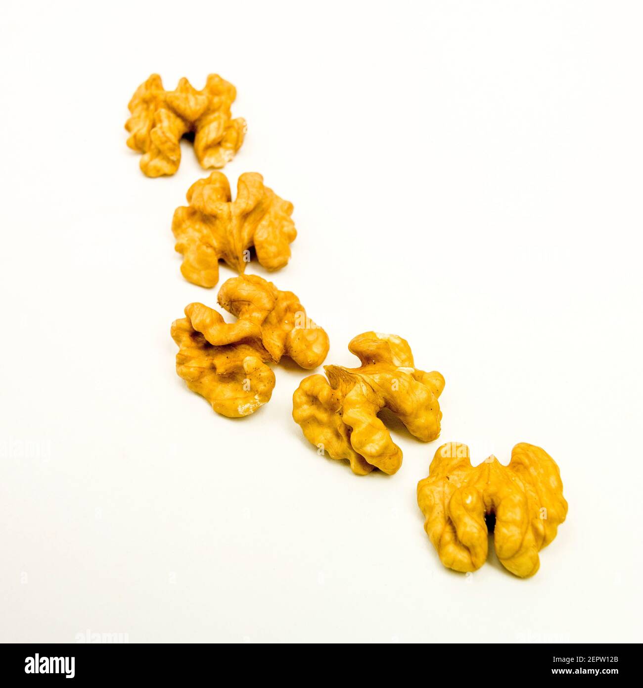 A close-up view of walnut pieces arranged neatly on a white surface ...