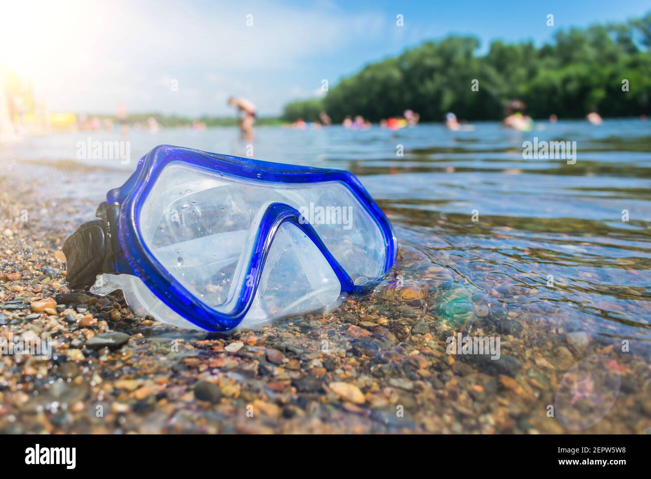 A swimming mask lies on a public beach near the water against the ...