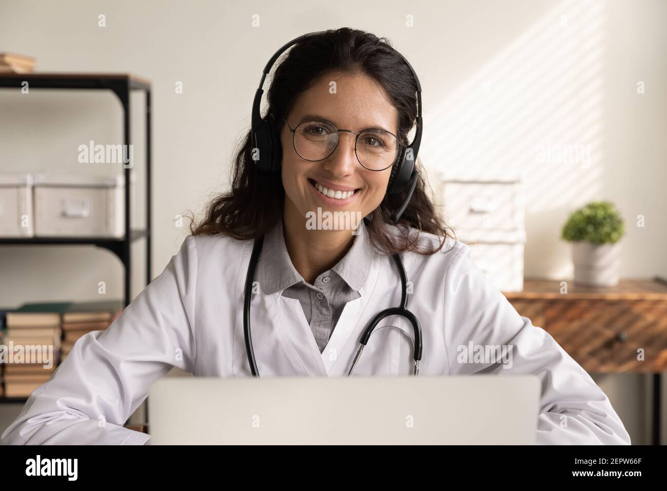 Head shot portrait smiling female doctor wearing headphones working ...