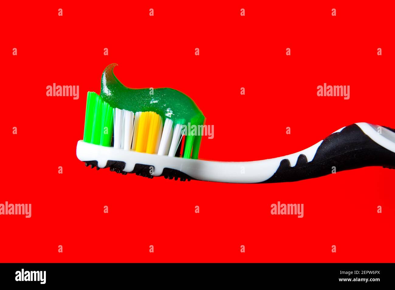 Green toothpaste beautifully lies on a toothbrush on a red background ...