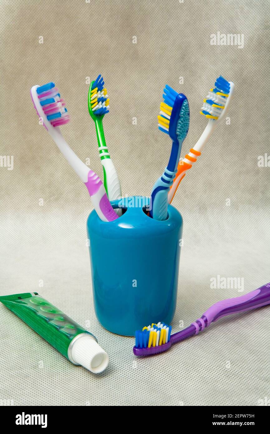 Multi-colored toothbrushes stand in a special glass next to a tube of ...