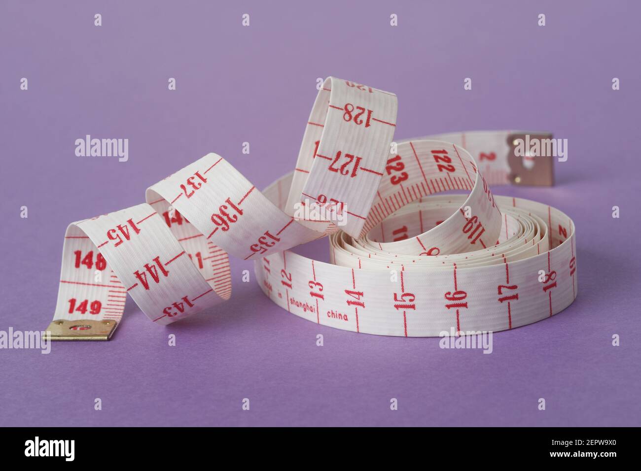 Measuring tape isolated on purple background and partially unwound into ...