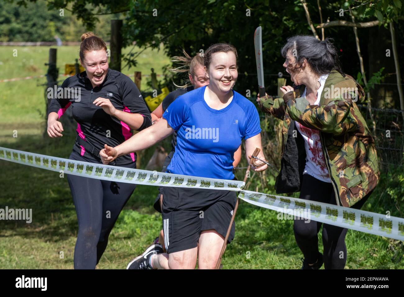 Three women runners laughing but still avoiding a woman zombie with a ...
