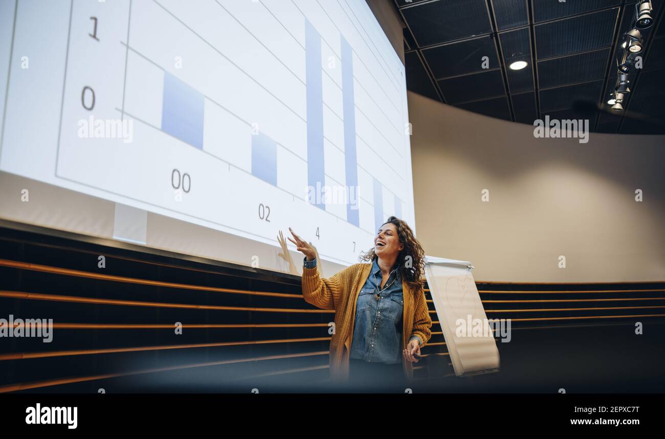 businesswoman pointing at projection screen and delivering a ...
