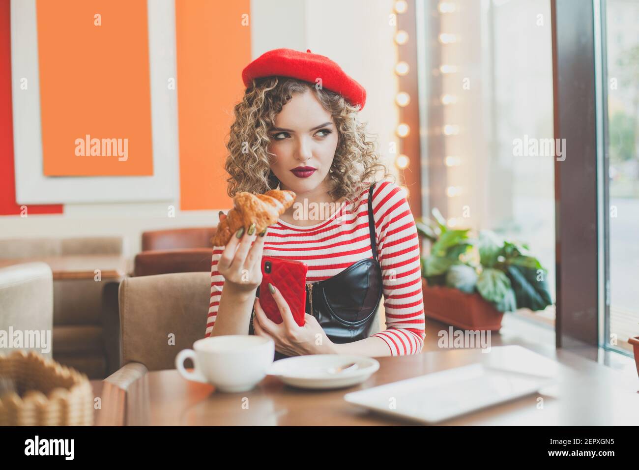 Young woman drinking coffee and looking at window in city street cafe ...