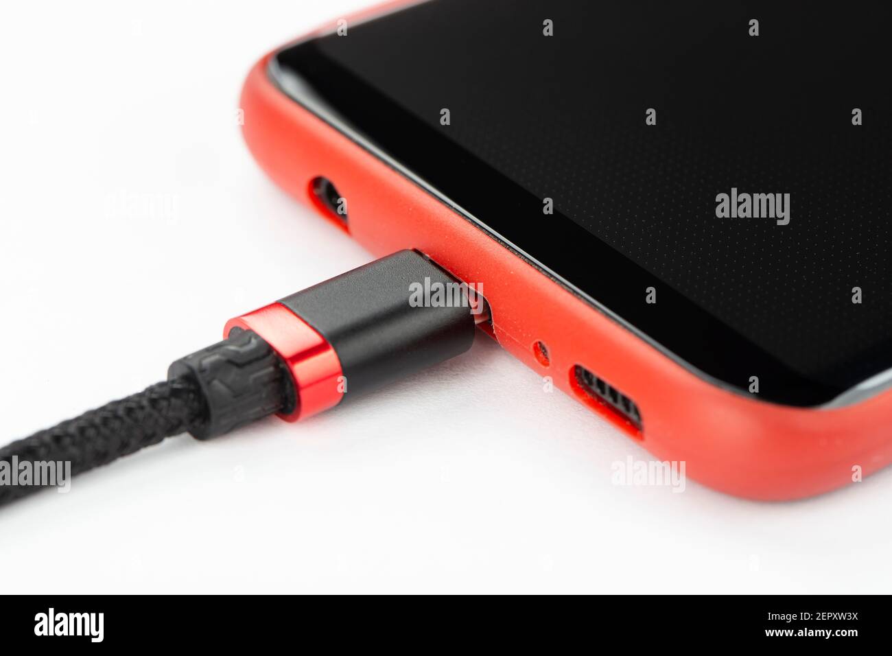 Mobile phone in a red case with a connected cable for charging power on ...