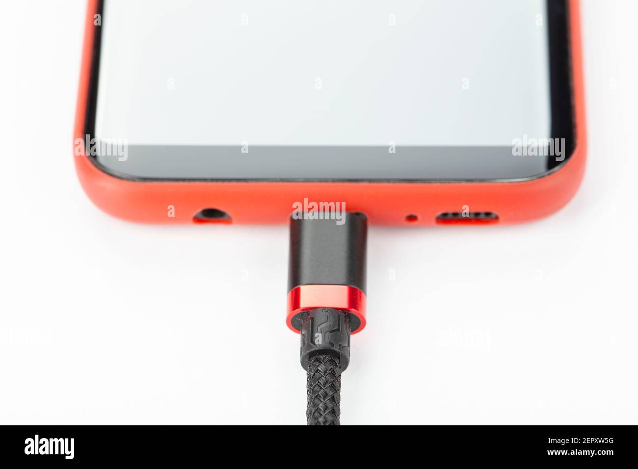 Mobile phone in a red case with a connected cable for charging power on ...