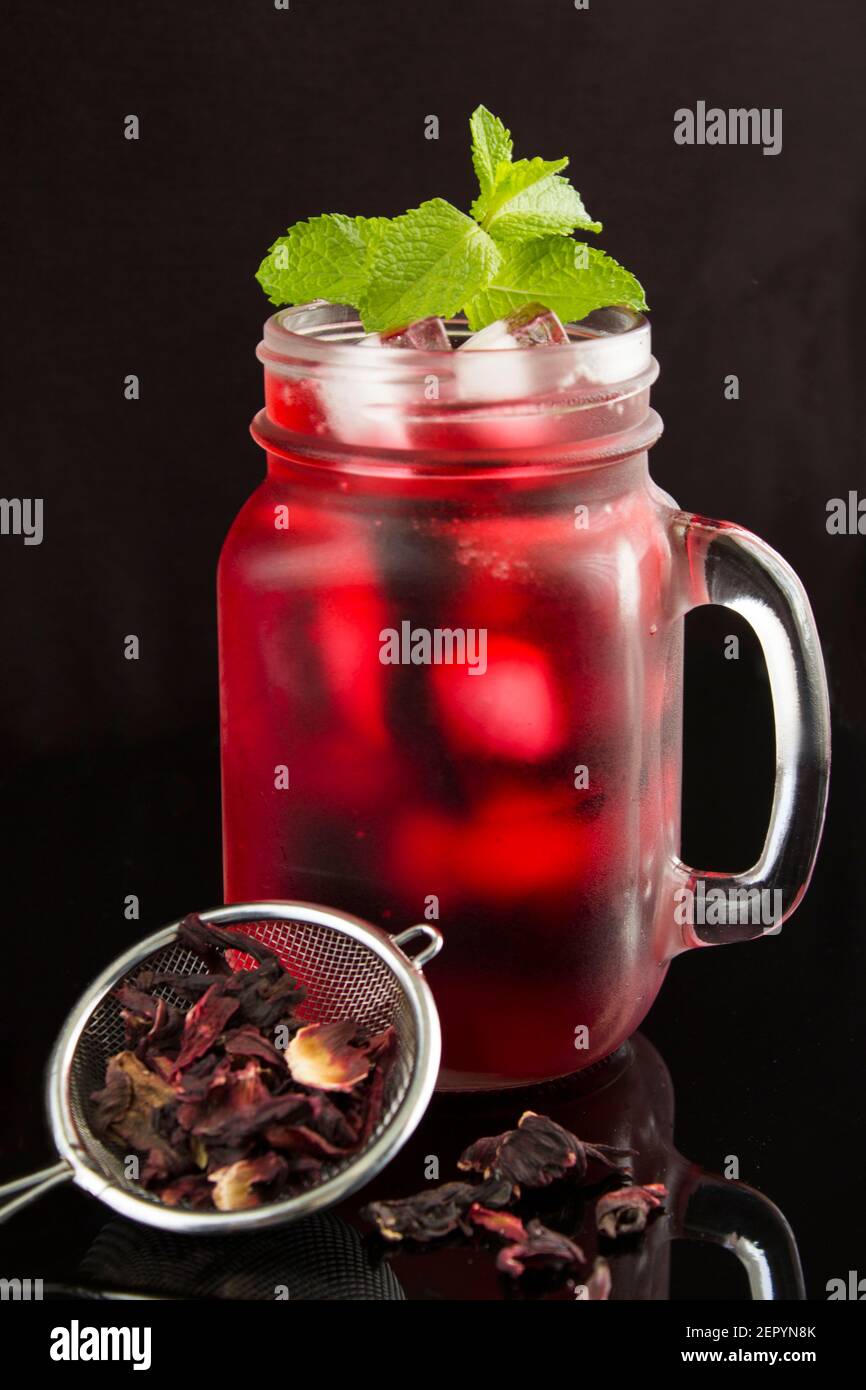 Iced hibiscus or karkade tea with mint in the glass on the black ...