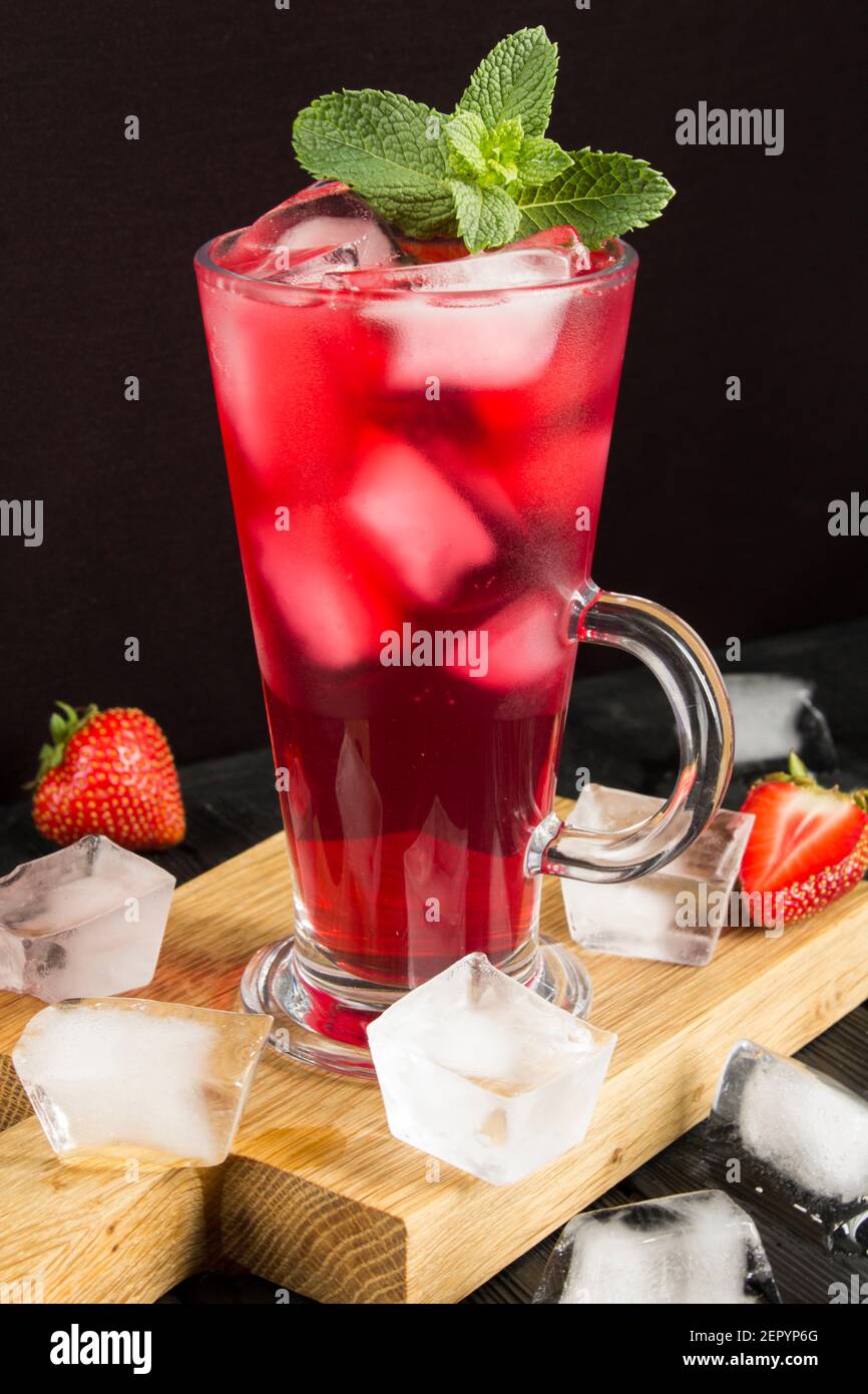 Cold pink lemonade with ice in the glass on the black background ...