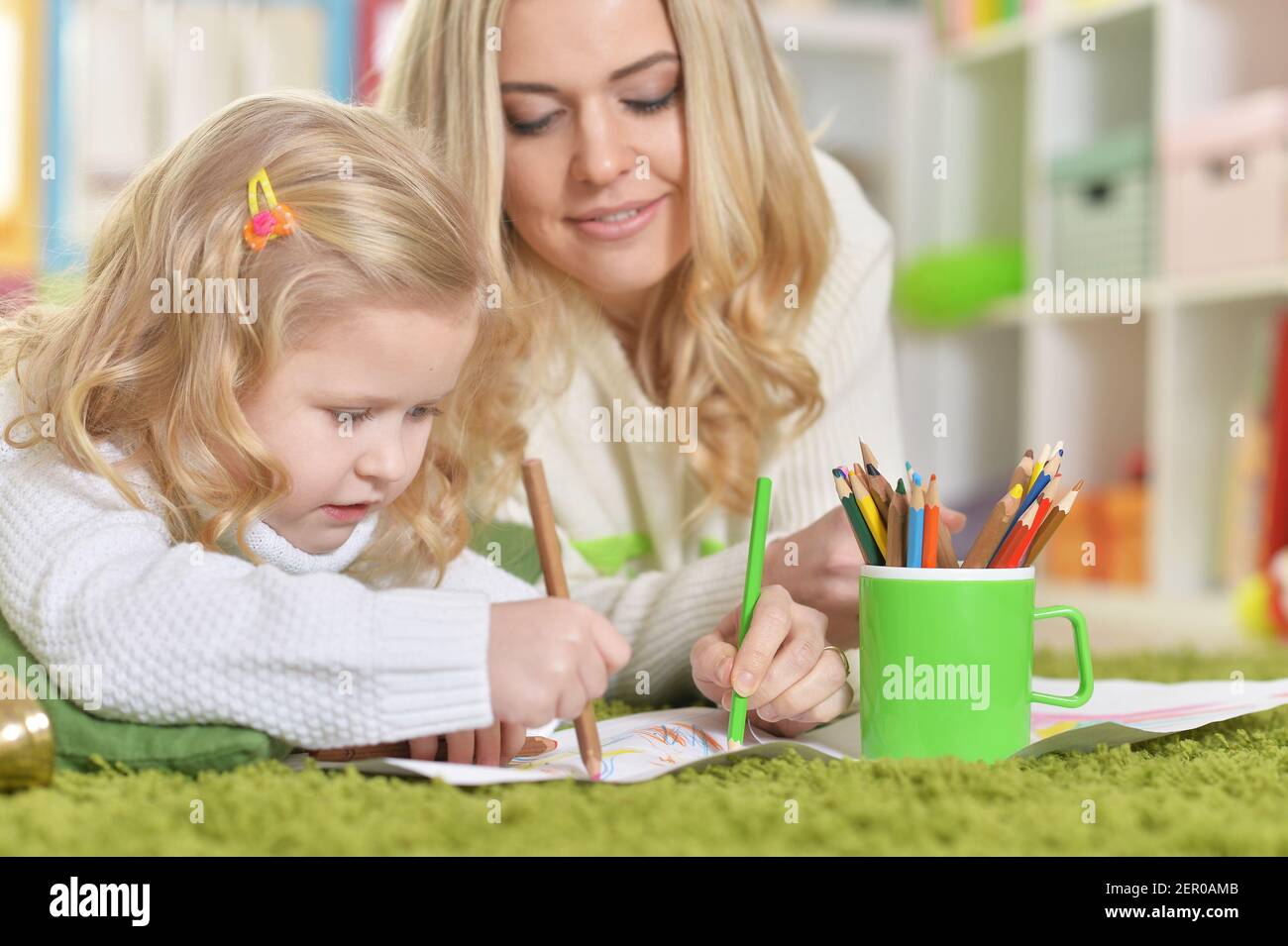 Mother with little daughter drawing with colorful pencils while lying ...
