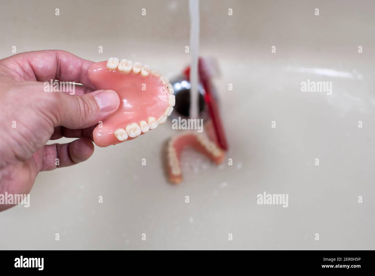 cleaning and washing of the teeth dentures in the sink with the running ...