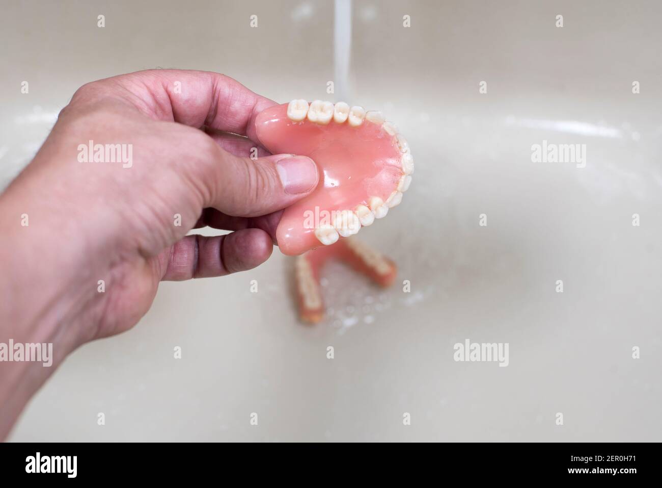 cleaning and washing of the teeth dentures in the sink with the running ...