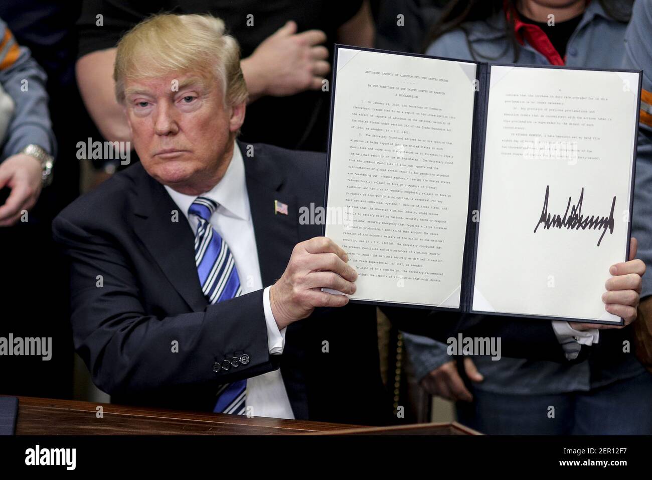 President Donald Trump holds up the 'Section 232 Proclamations' to ...