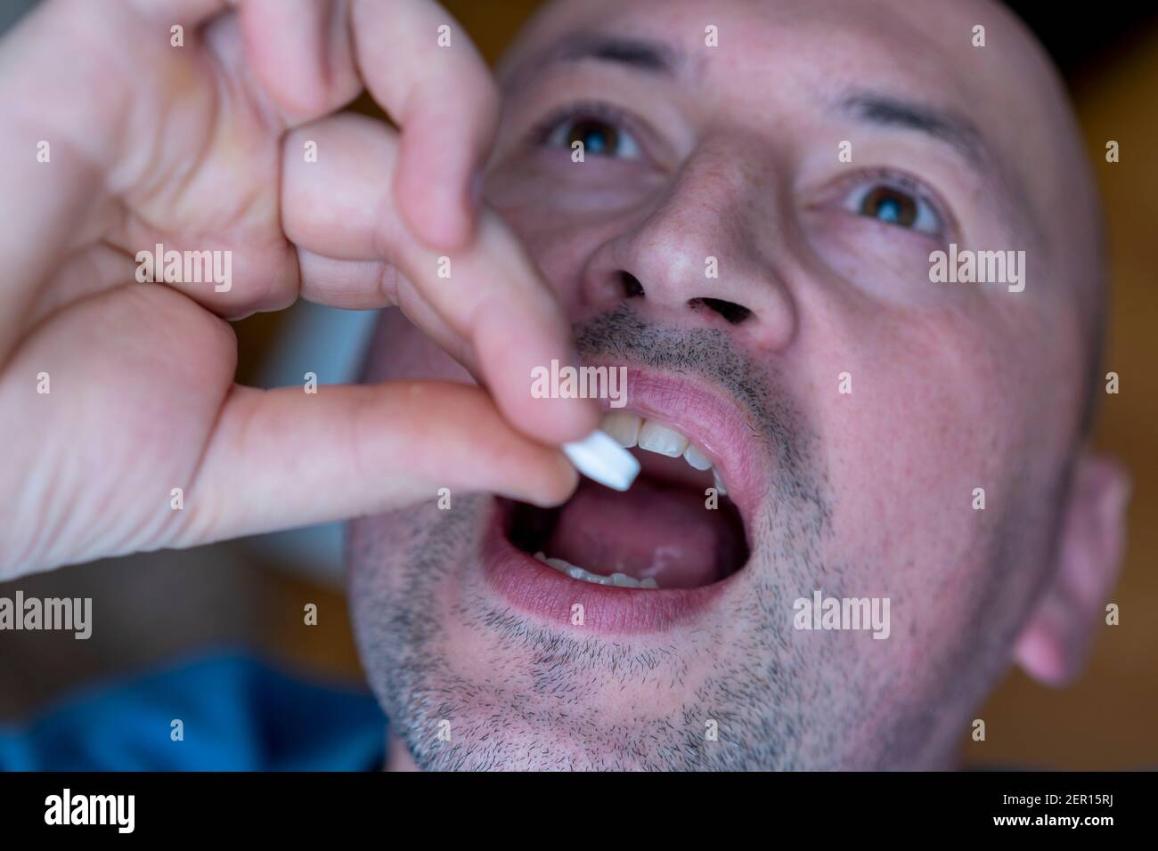 Extreme closeup man face taking white pill, mouth view swallowing pills ...
