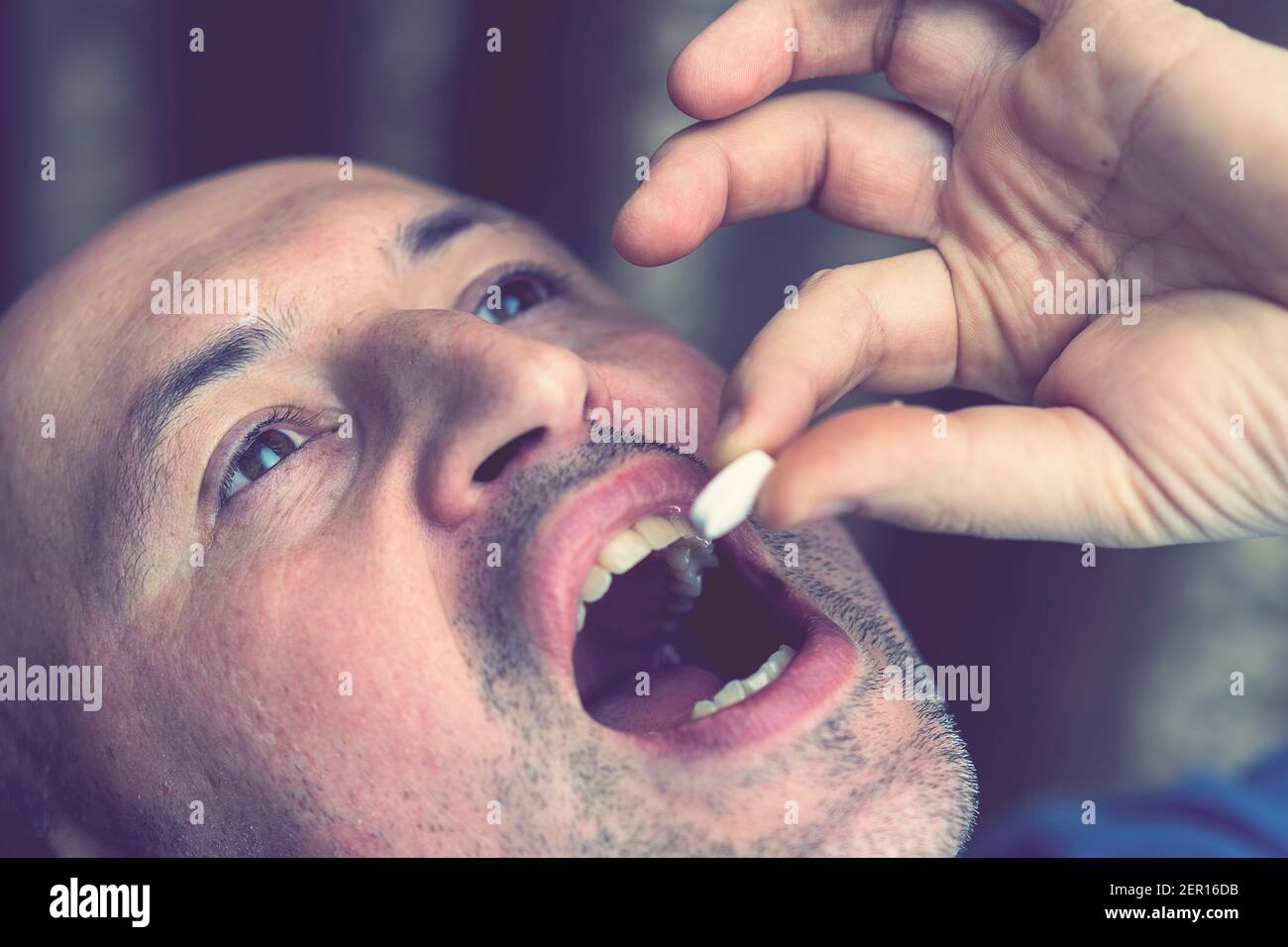 Extreme closeup man face taking white pill, mouth view swallowing pills ...