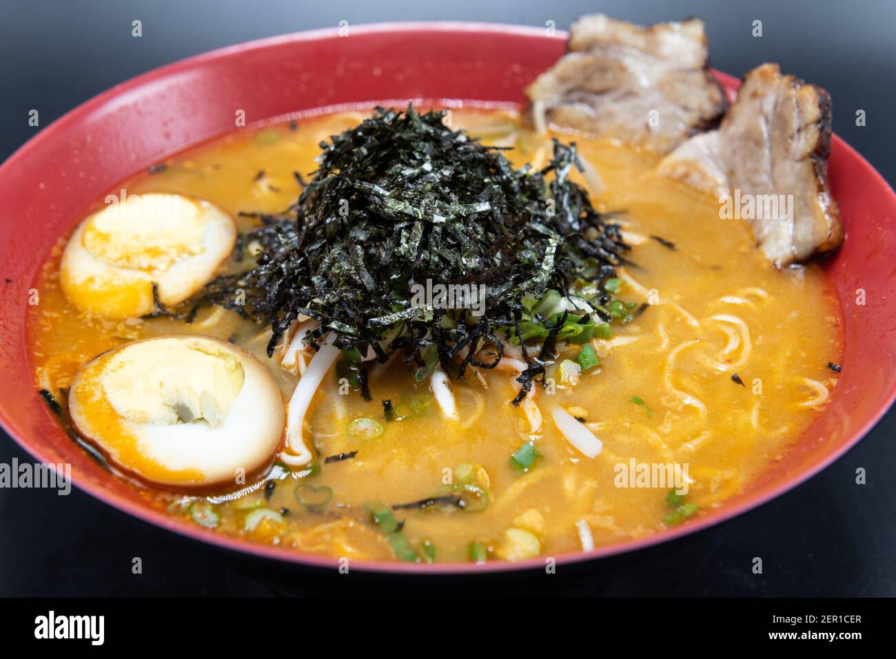 Large Bowl Of Spicy Volcano Ramen Served With A Pile Of Seaweed On Top With Braised Pork And