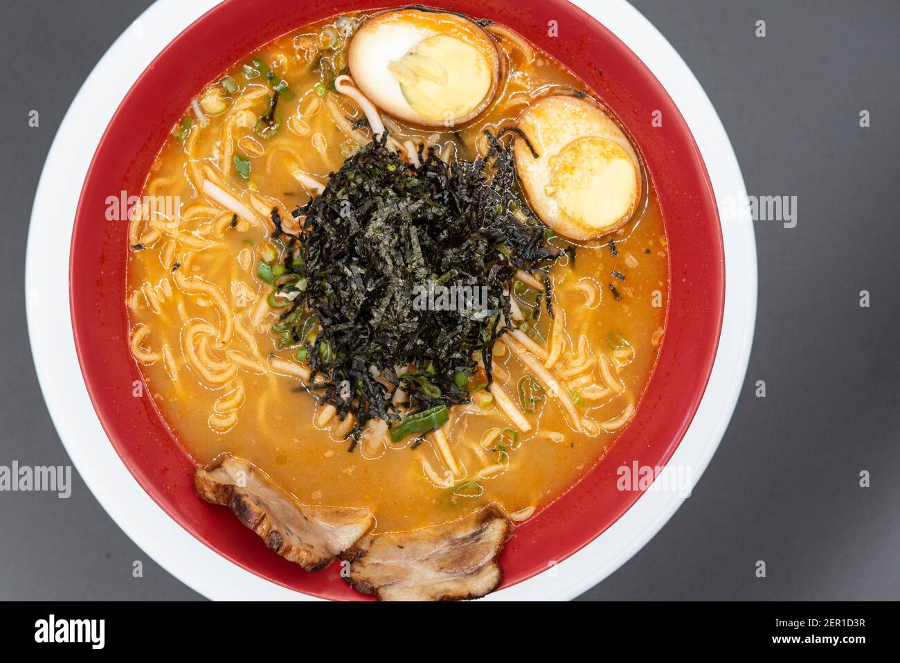 Overhead view of large bowl of spicy Volcano Ramen served with a pile ...