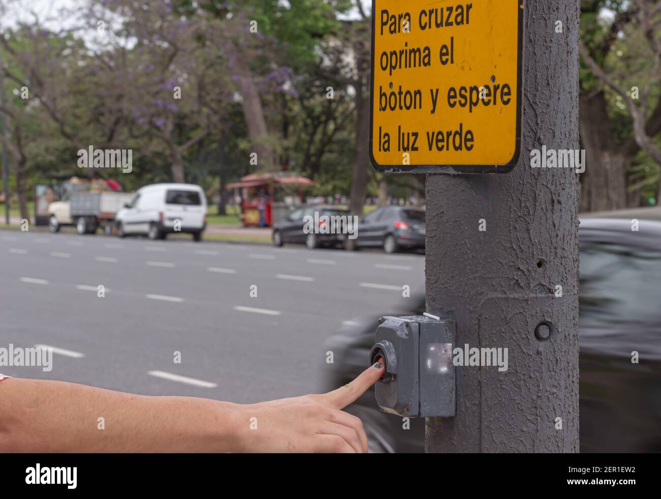 Sign indicating in spanish: to cross, press the button and wait for the ...