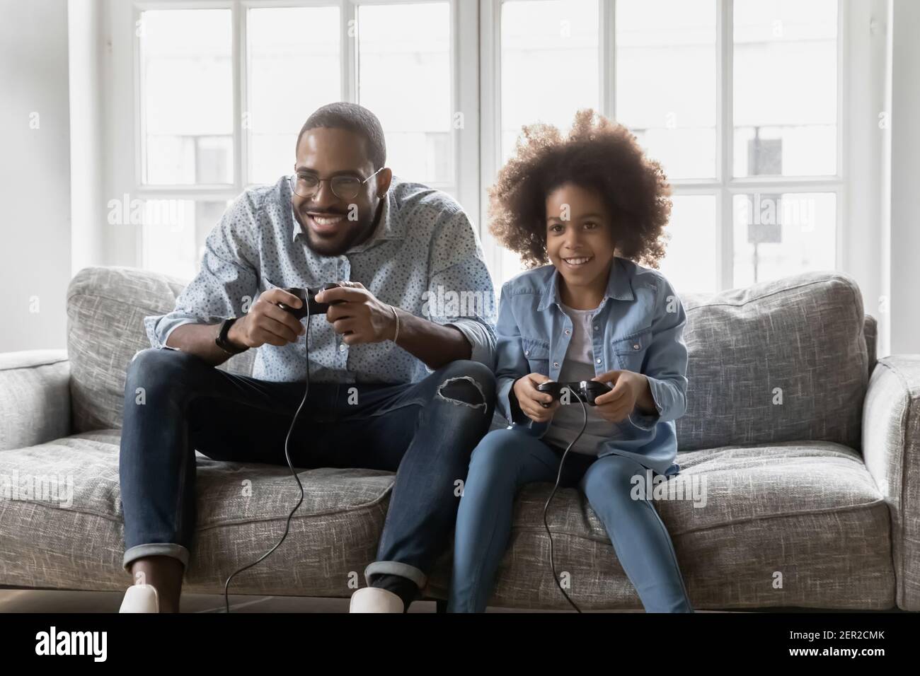Excited girl and her dad playing video games together Stock Photo - Alamy