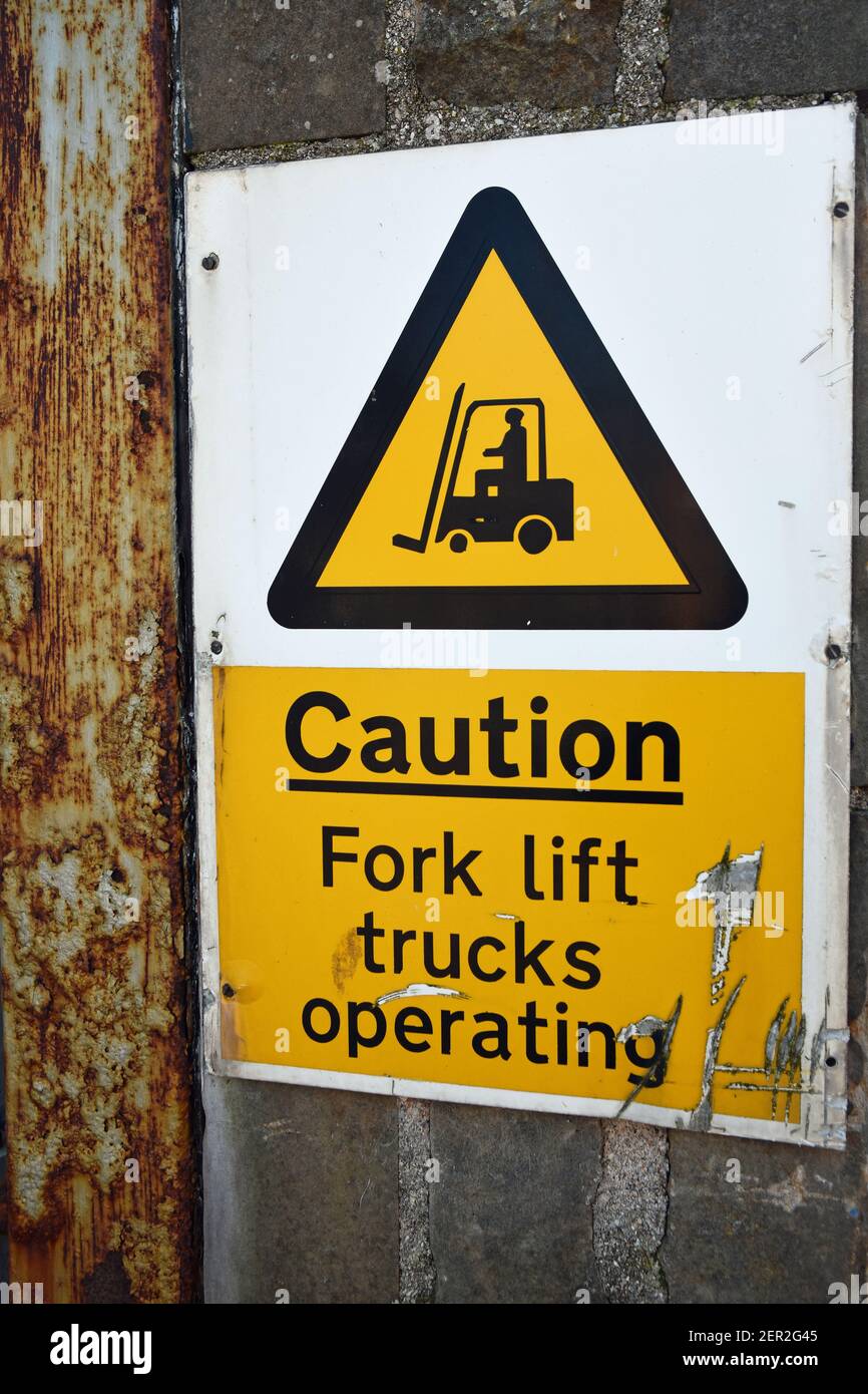Caution fork lift trucks operating sign against industrial wall ...
