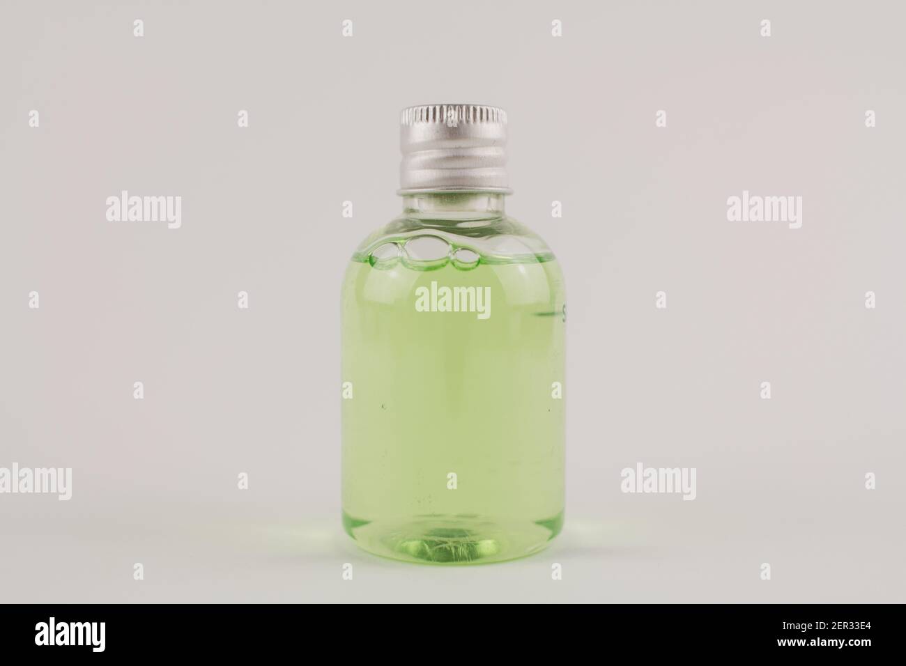 a light green shampoo in a transparent bottle on a white background ...