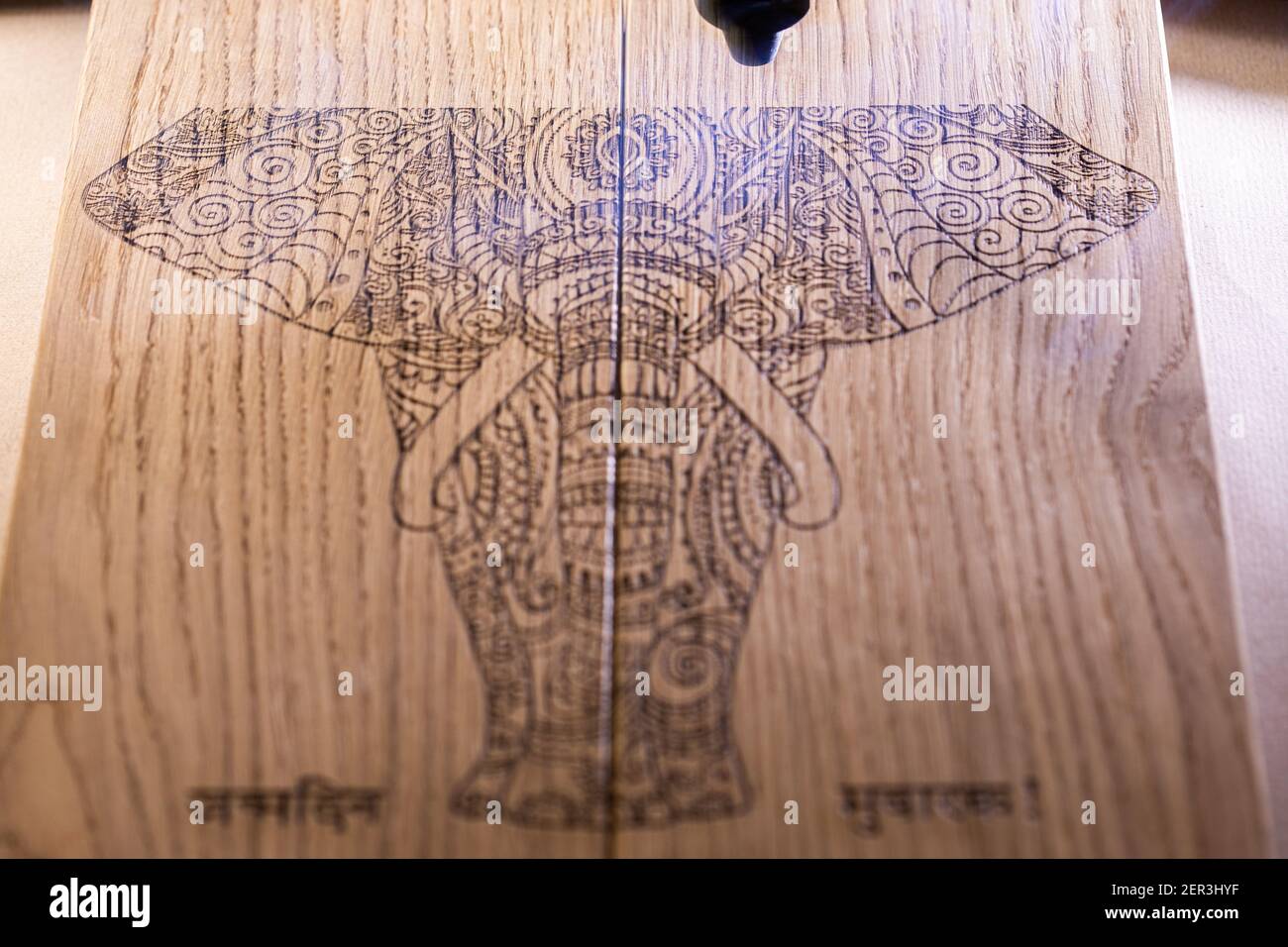 laser engraves the image of an Indian elephant on a wooden surface ...