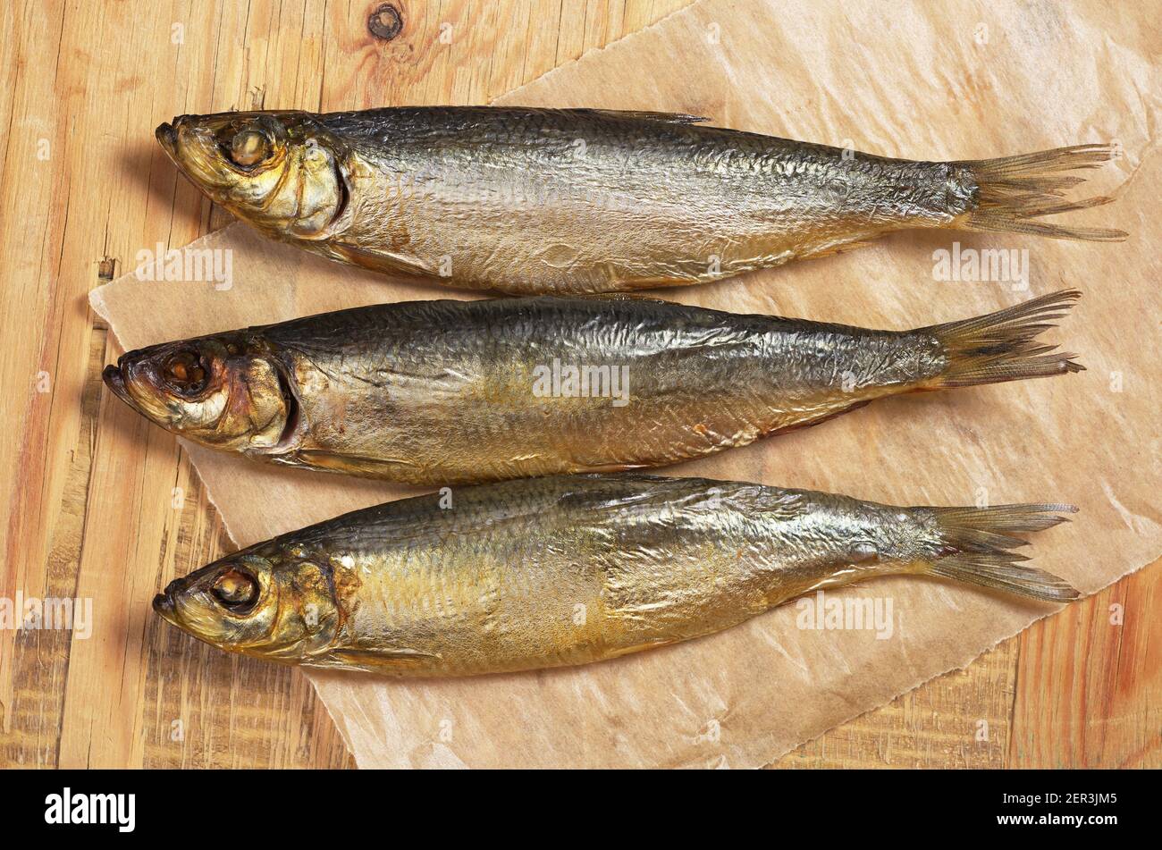 Smoked herring in paper on old wooden table close up, top view Stock ...