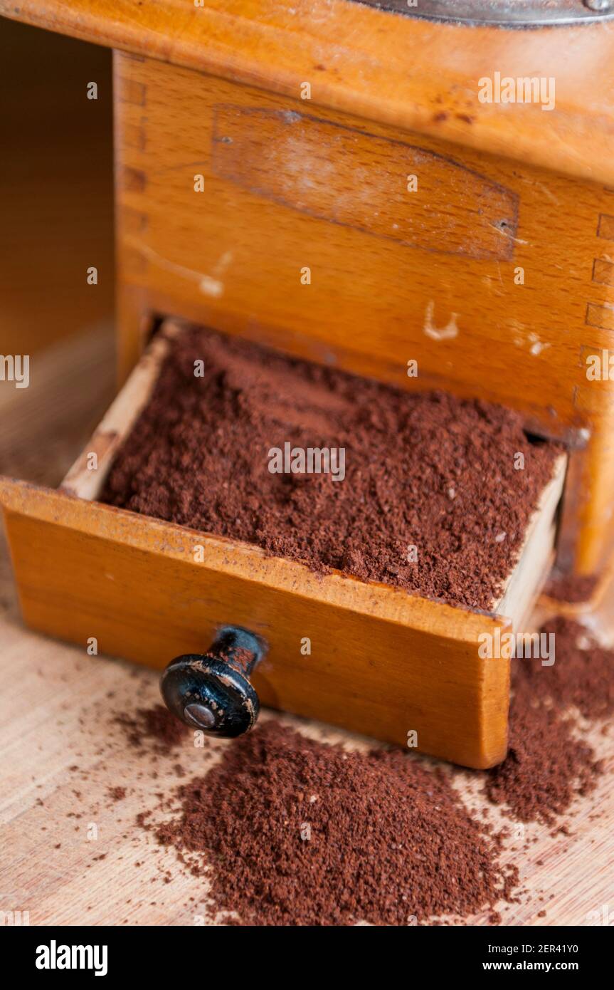 Partial view of a manual wooden coffee grinder with an open drawer and ...