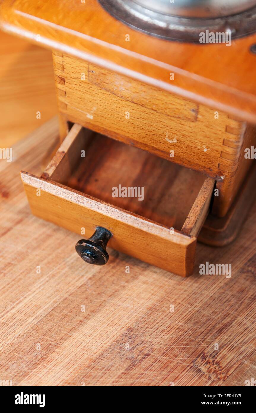 Partial view of manual wooden coffee grinder with open drawer on worn ...