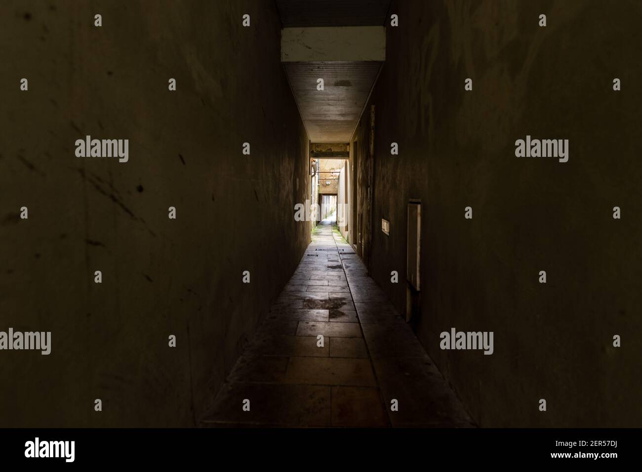 A dark, spooky corridor leading to a lit area with no people. Taken ...