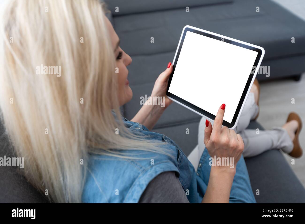 hands holding smart tablet with app smart home on home living room as ...