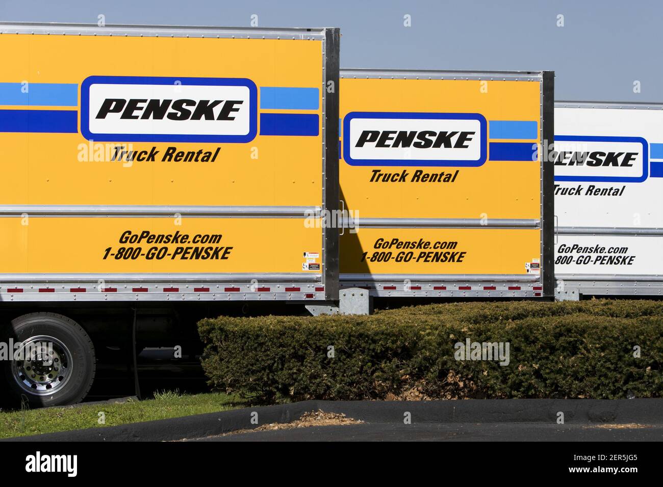 A logo sign and rental trucks outside of a facility occupied by Penske ...
