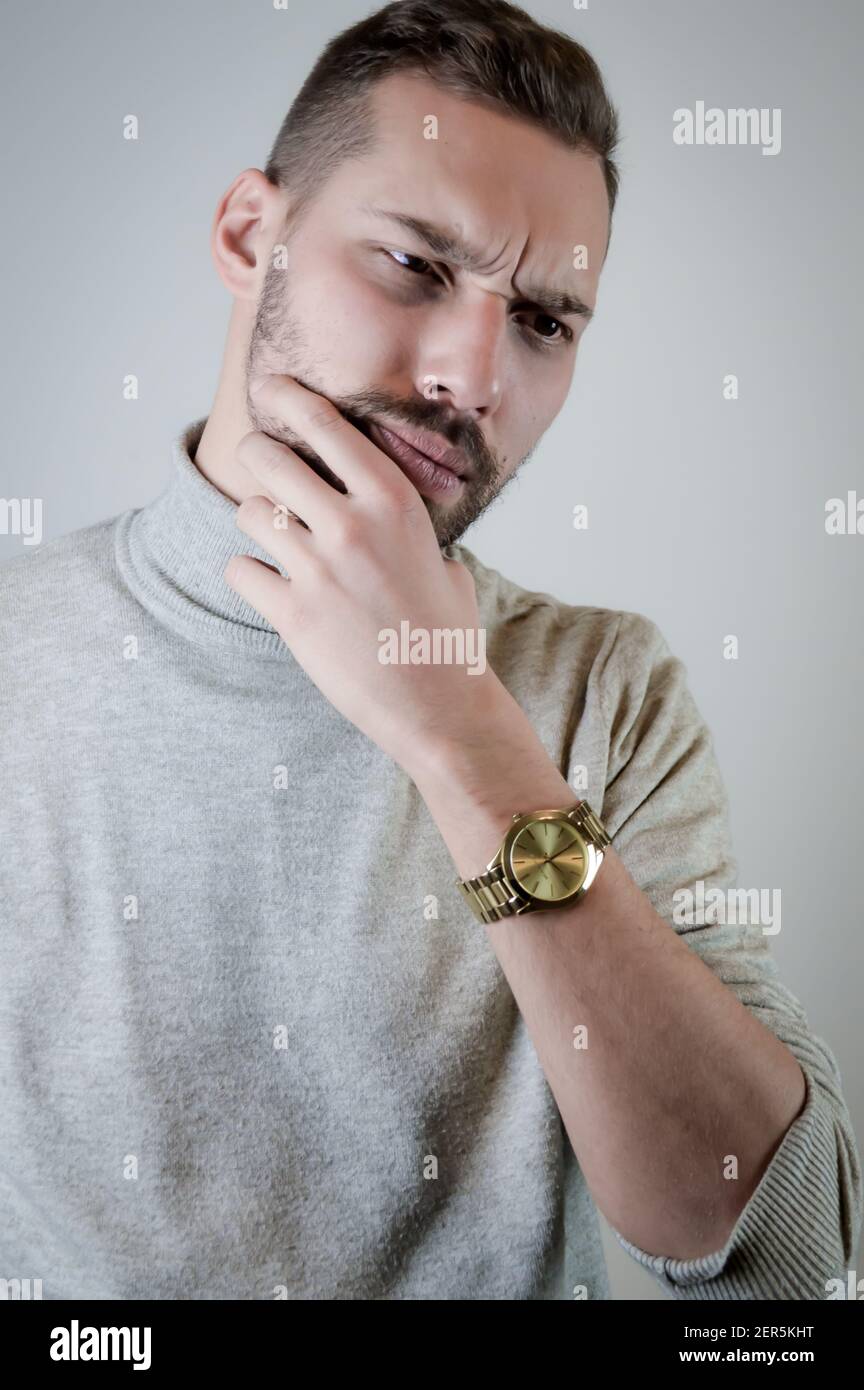 Portrait of a young man touching his chin in a moment of doubt or ...
