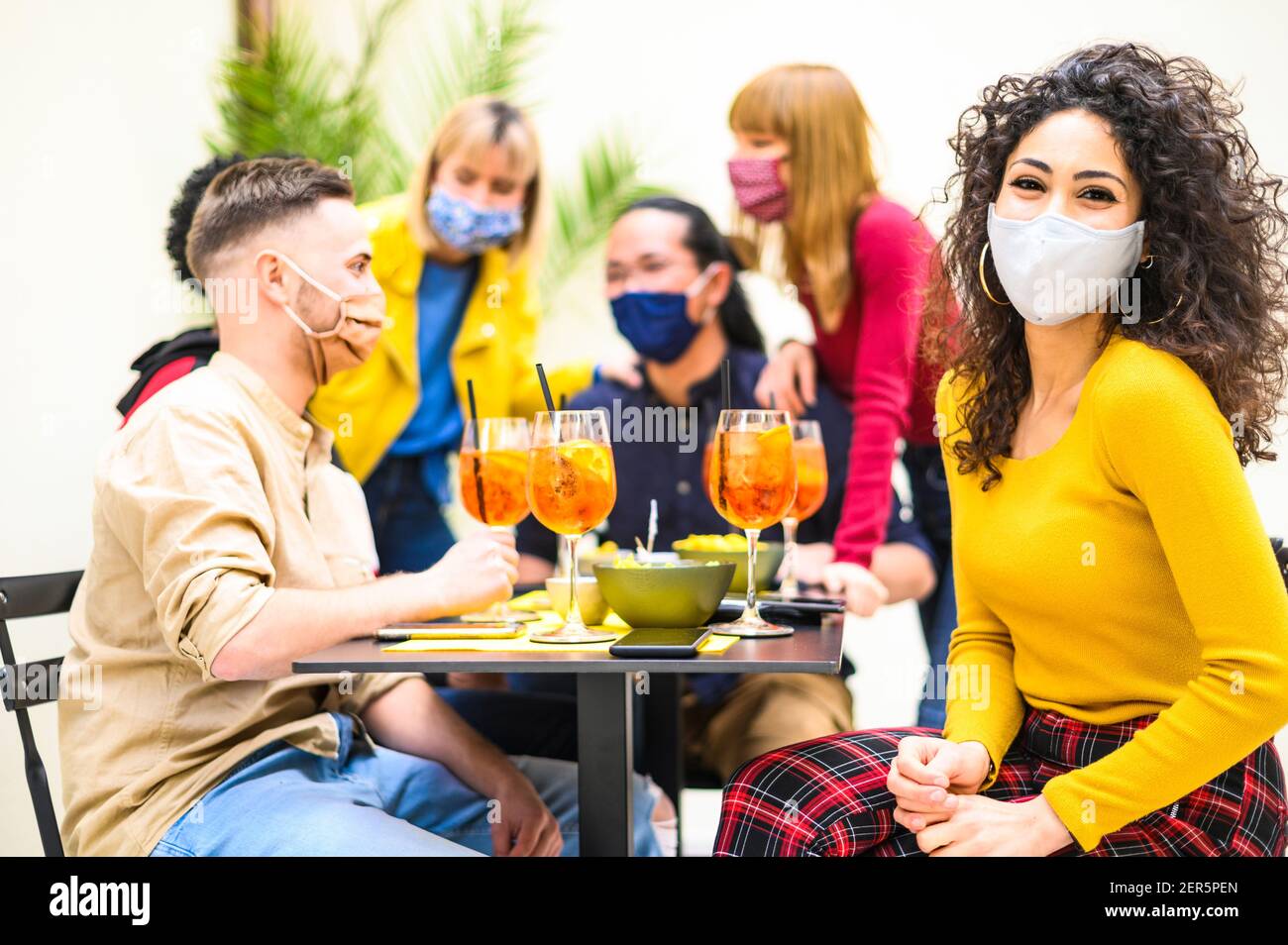 Multiracial people drinking spritz with open face mask at cocktail bar ...
