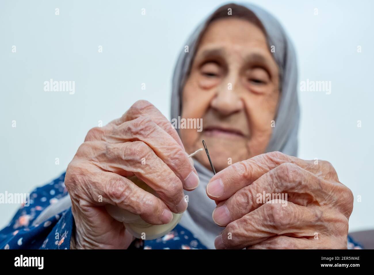 Arabic muslim old woman inserting thread in needle Stock Photo - Alamy