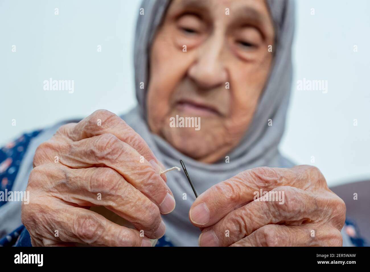 Arabic muslim old woman inserting thread in needle Stock Photo - Alamy