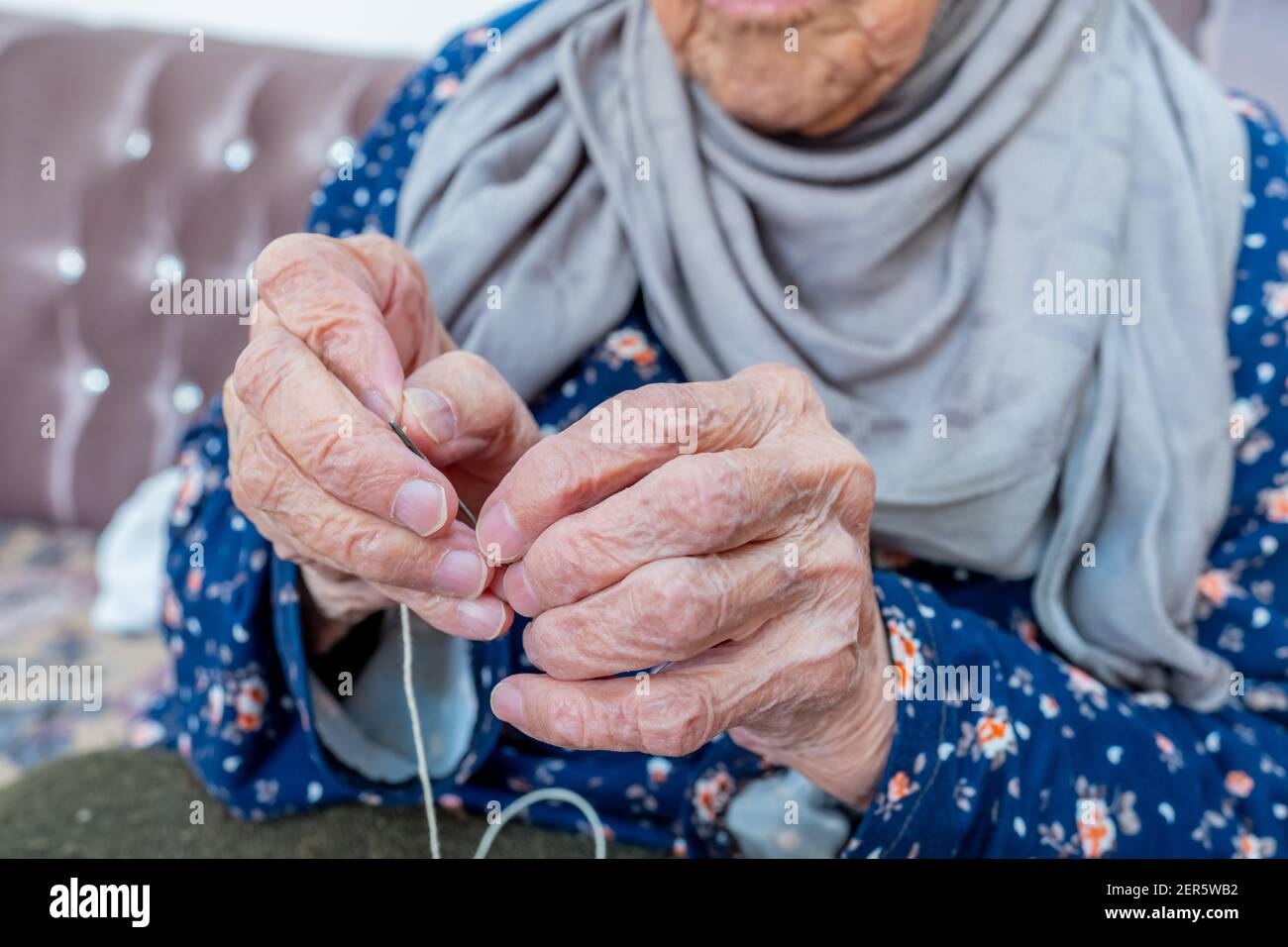 Arabic muslim old woman inserting thread in needle Stock Photo - Alamy