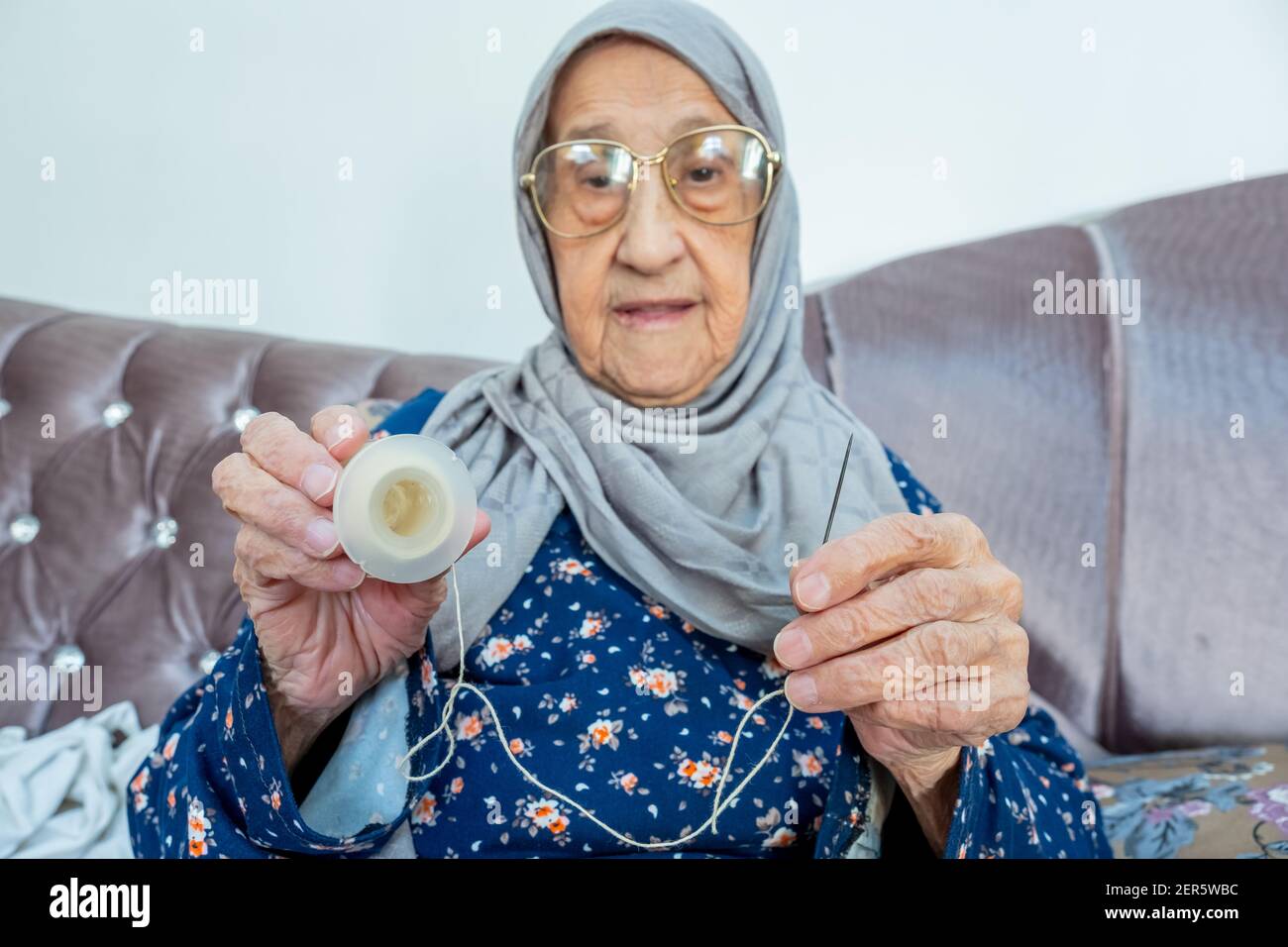 Arabic muslim old woman inserting thread in needle Stock Photo - Alamy