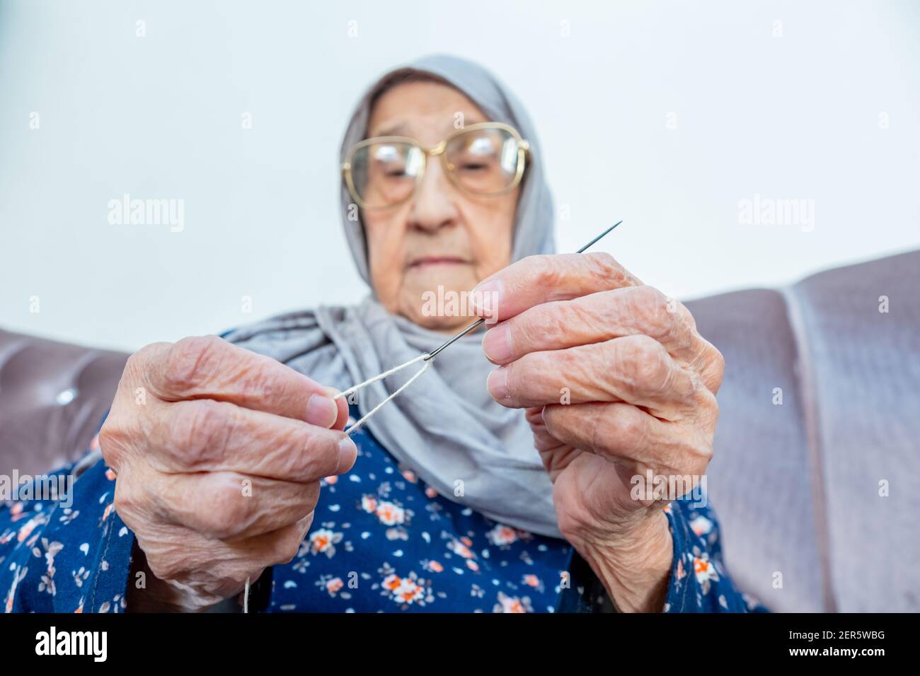 Arabic muslim old woman inserting thread in needle Stock Photo - Alamy