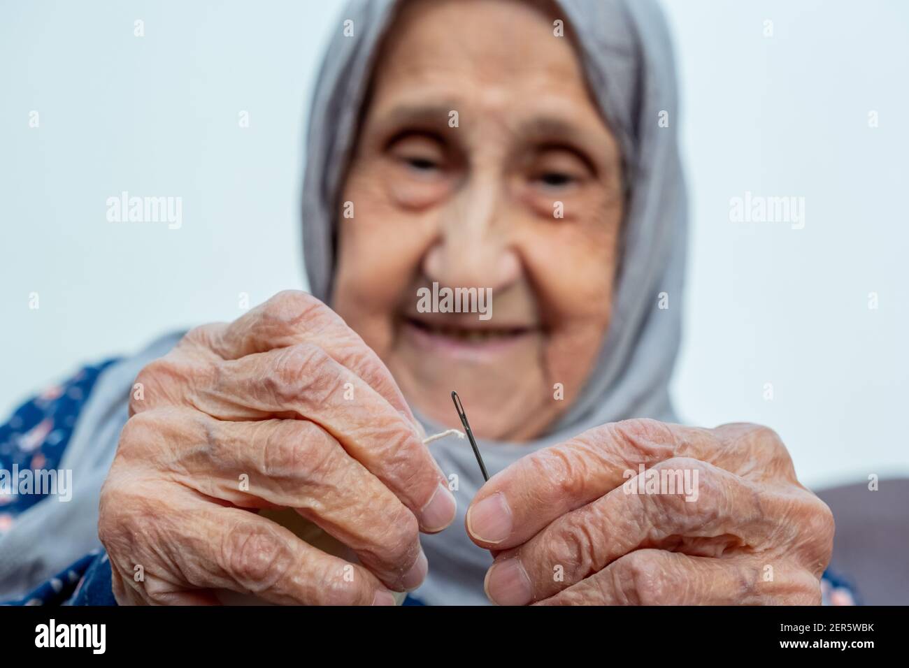 Arabic muslim old woman inserting thread in needle Stock Photo - Alamy