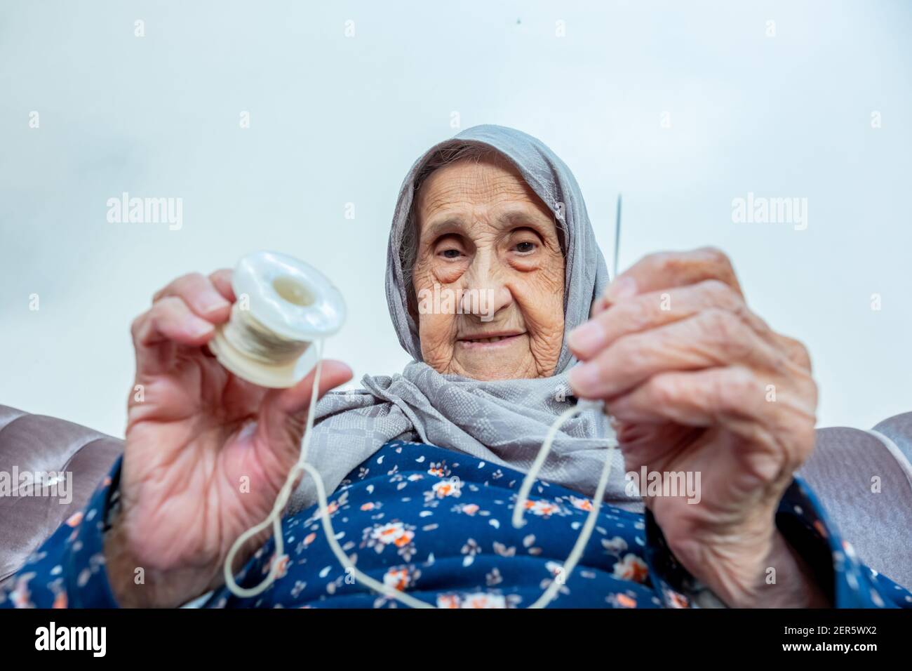 Arabic muslim old woman inserting thread in needle Stock Photo - Alamy