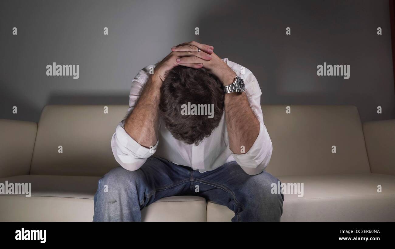 man at home in despair - young depressed and desperate man crying on ...