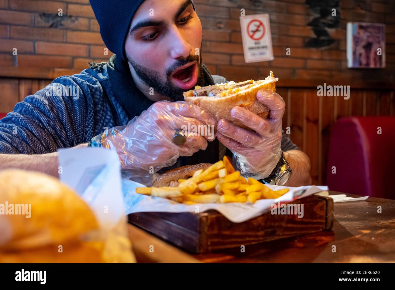 Arabic man at restaurant eating burger Stock Photo - Alamy