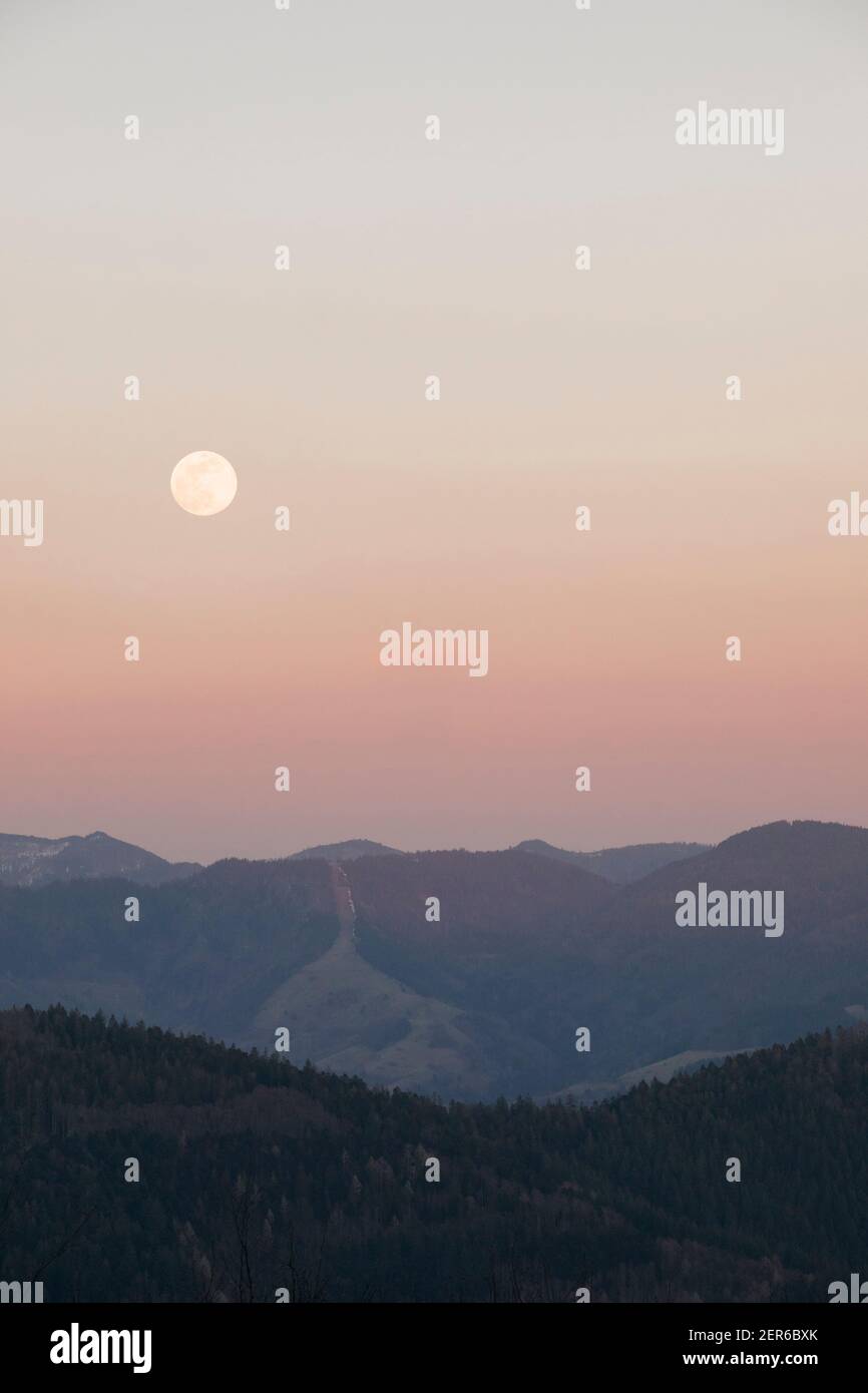 Scenic full moon above mountain peaks with sunset orange sky Stock ...